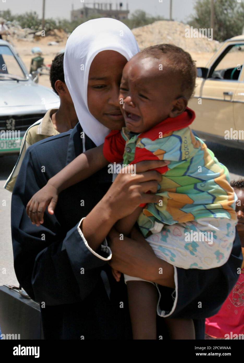 A Palestinian girl holds a crying baby as residents of Rafah in the ...