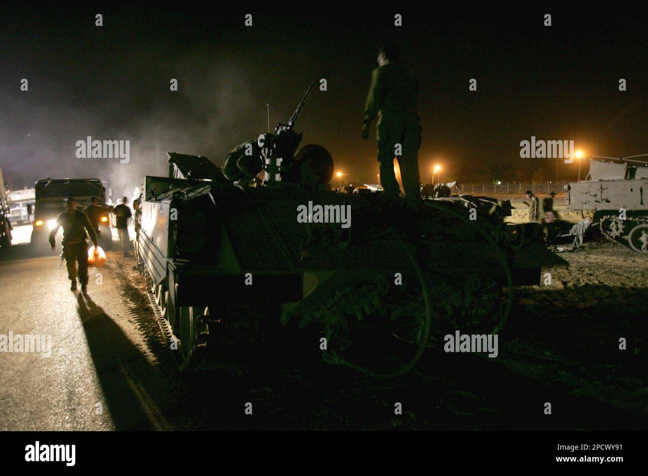 Israeli soldiers and armored vehicles are seen on stand by at an army ...