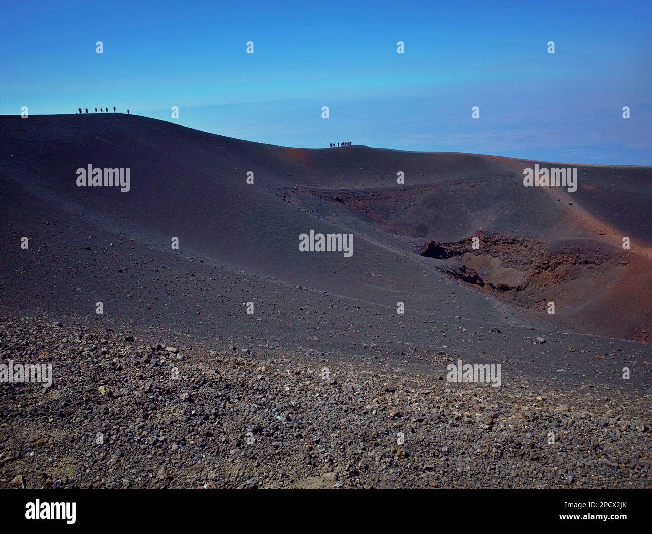 Barren mountain people walking across empty landscape under blue sky ...