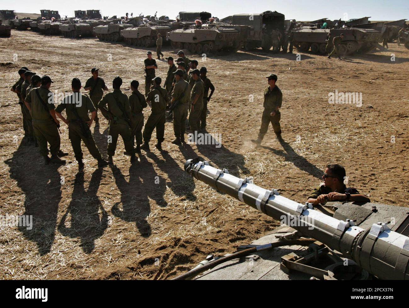 Israeli soldiers listen to their commander next to a line of armored ...