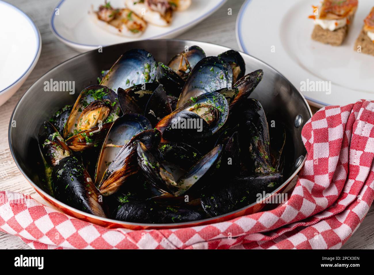 Baked blue mussels in spicy with lemon in a black cast-iron pot Stock ...