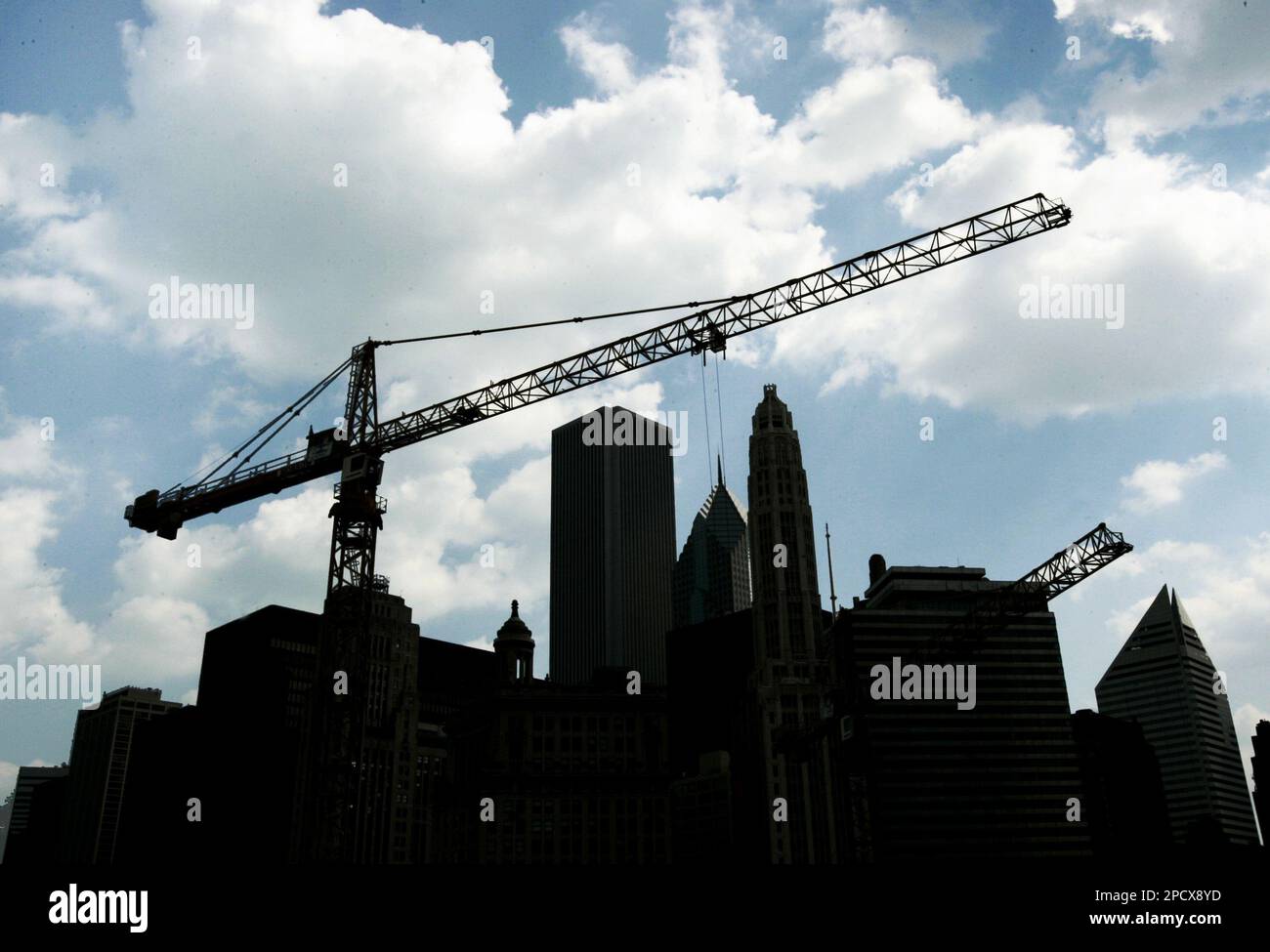 Construction cranes are silhouetted at a high-rise project in downtown ...