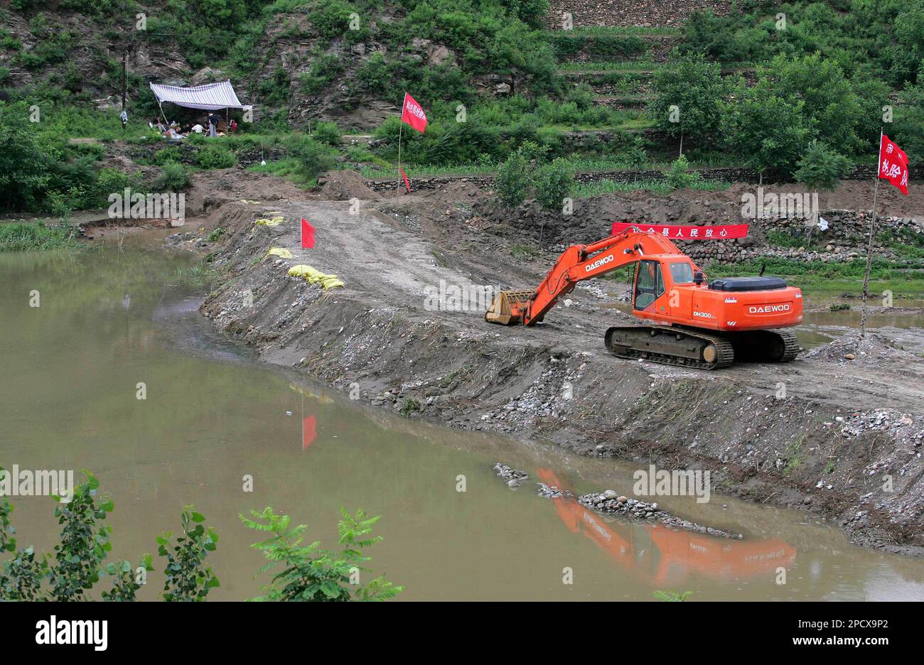 Workers monitor a dam built to redirect the flow of water in the Dasha ...