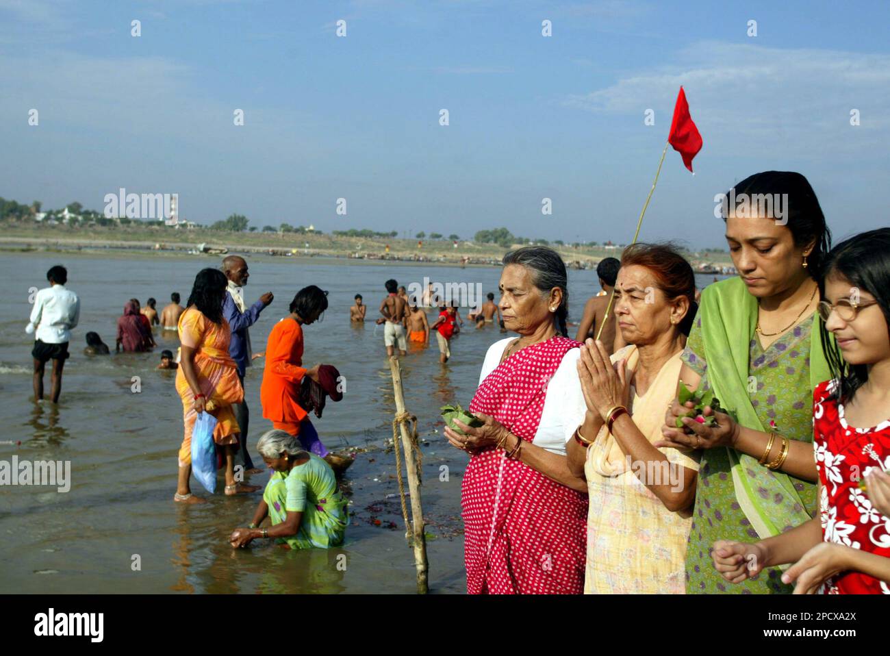 Hindu devotees pray after taking a holy dip at the Sangam, the ...
