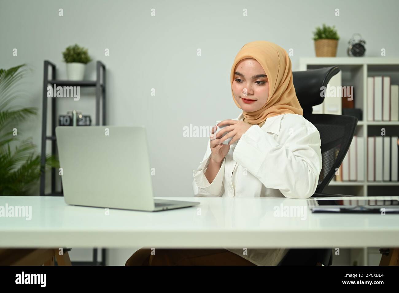 Portrait of muslim woman corporate CEO in hijab holding cup of coffee ...