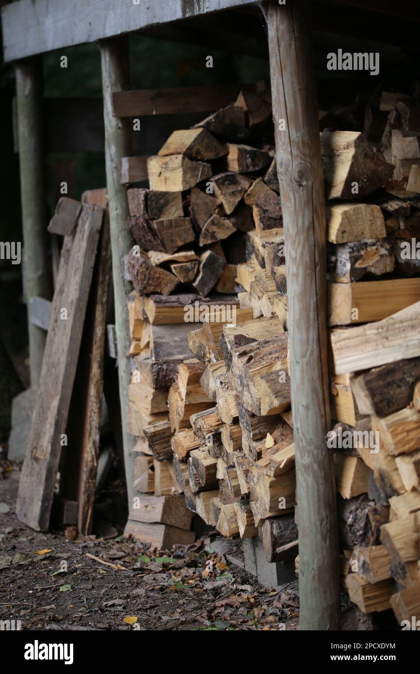 A pile of wooden logs situated in front of a structure Stock Photo - Alamy