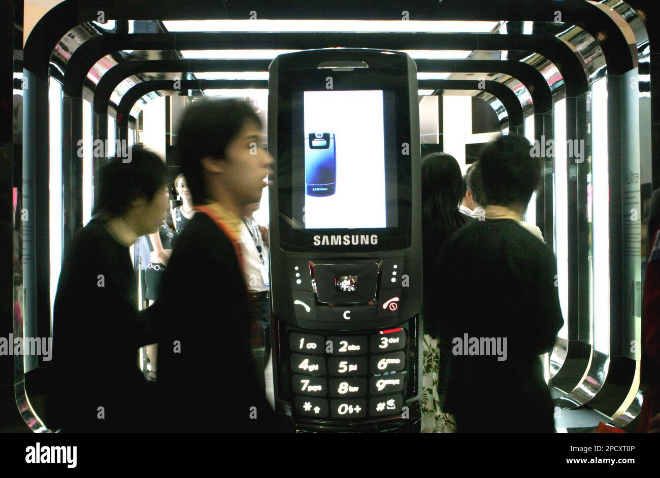 Visitors walk past a giant mobile phone on display during one of Asia's ...