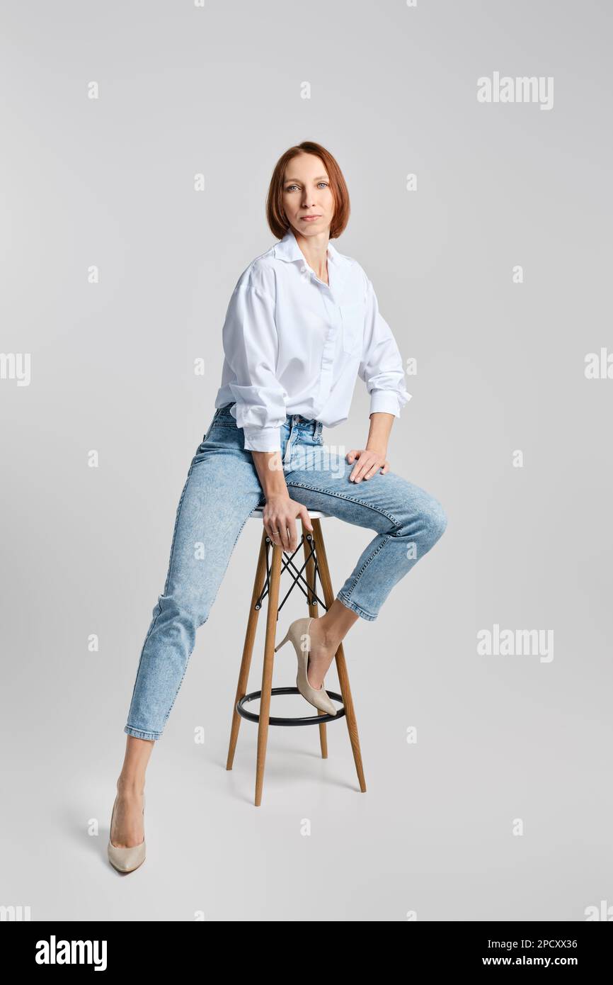 Casual portrait of middle aged redhead woman in white shirt and blue ...