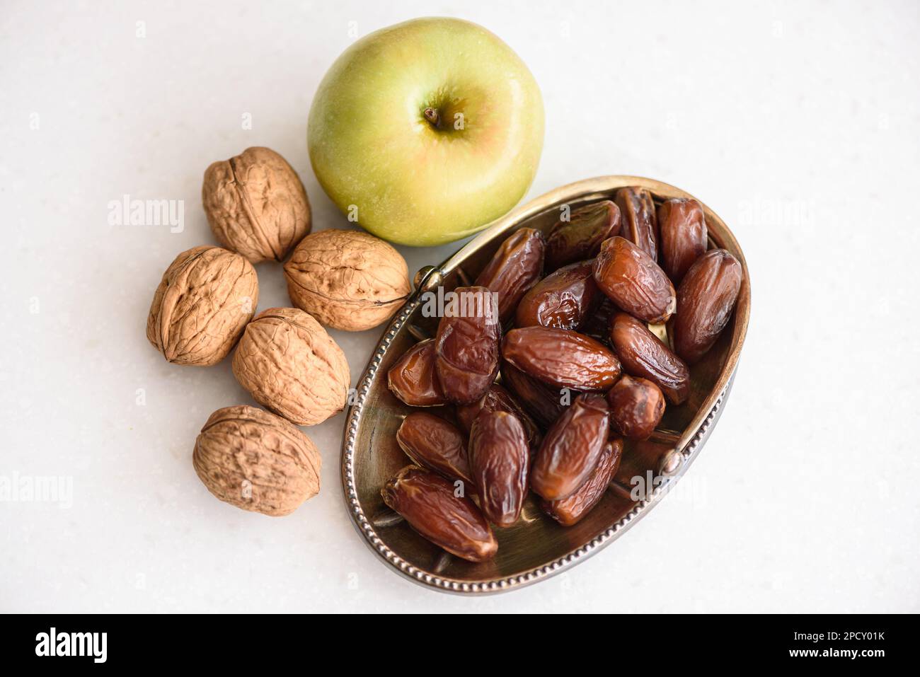 Green apple, walnuts and date fruits on white background Stock Photo ...