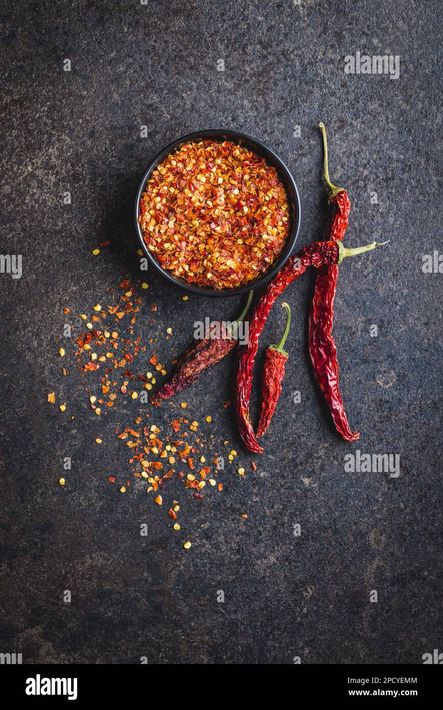 Dry chili pepper flakes. Crushed red peppers on the black table. Top ...