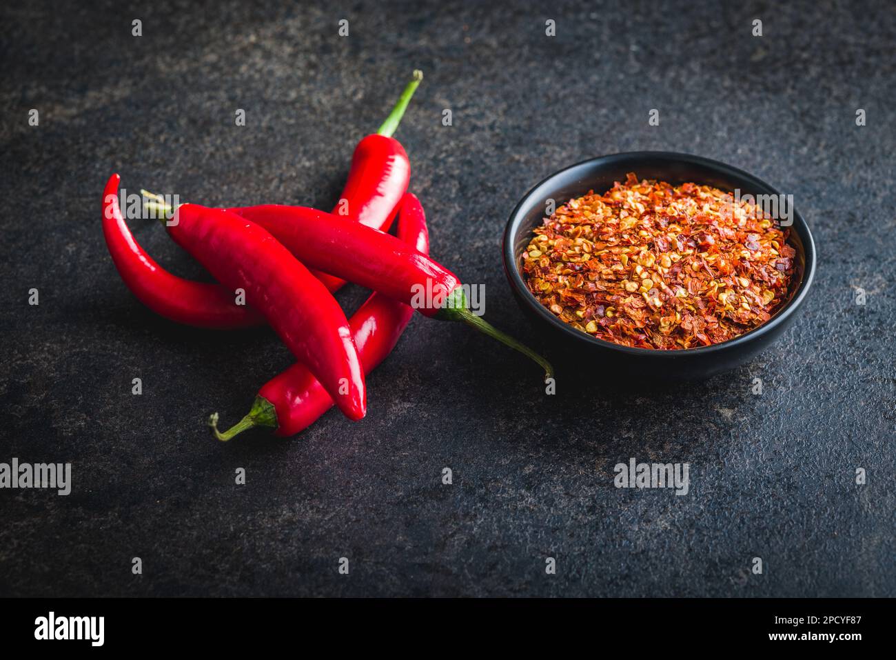 Dry chili pepper flakes. Crushed red peppers in bowl on the black table ...