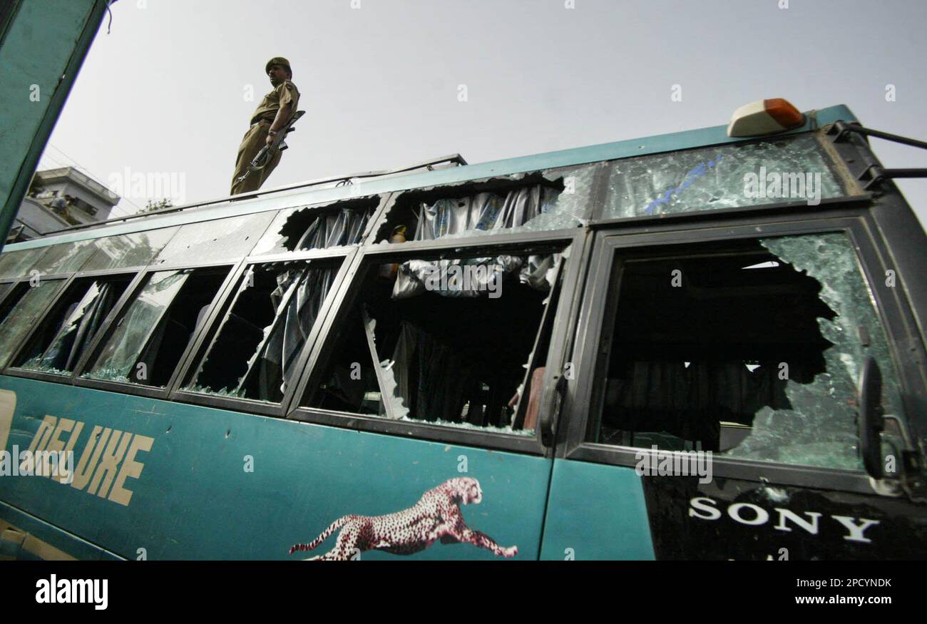 A security personnel stands on a bus that was damaged in a grenade ...