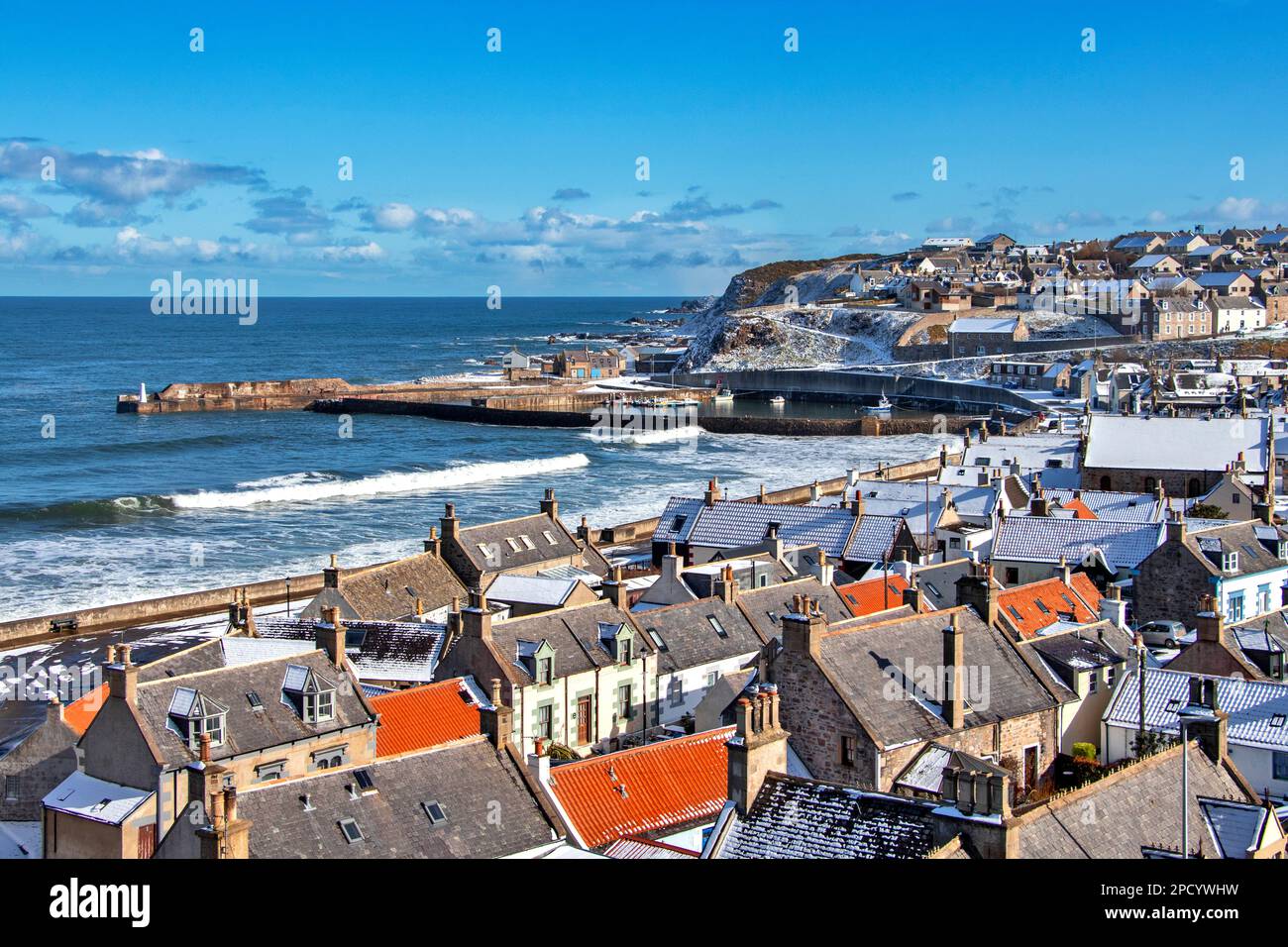 Cullen Bay Moray Scotland a blue sky snow covered houses and waves at ...