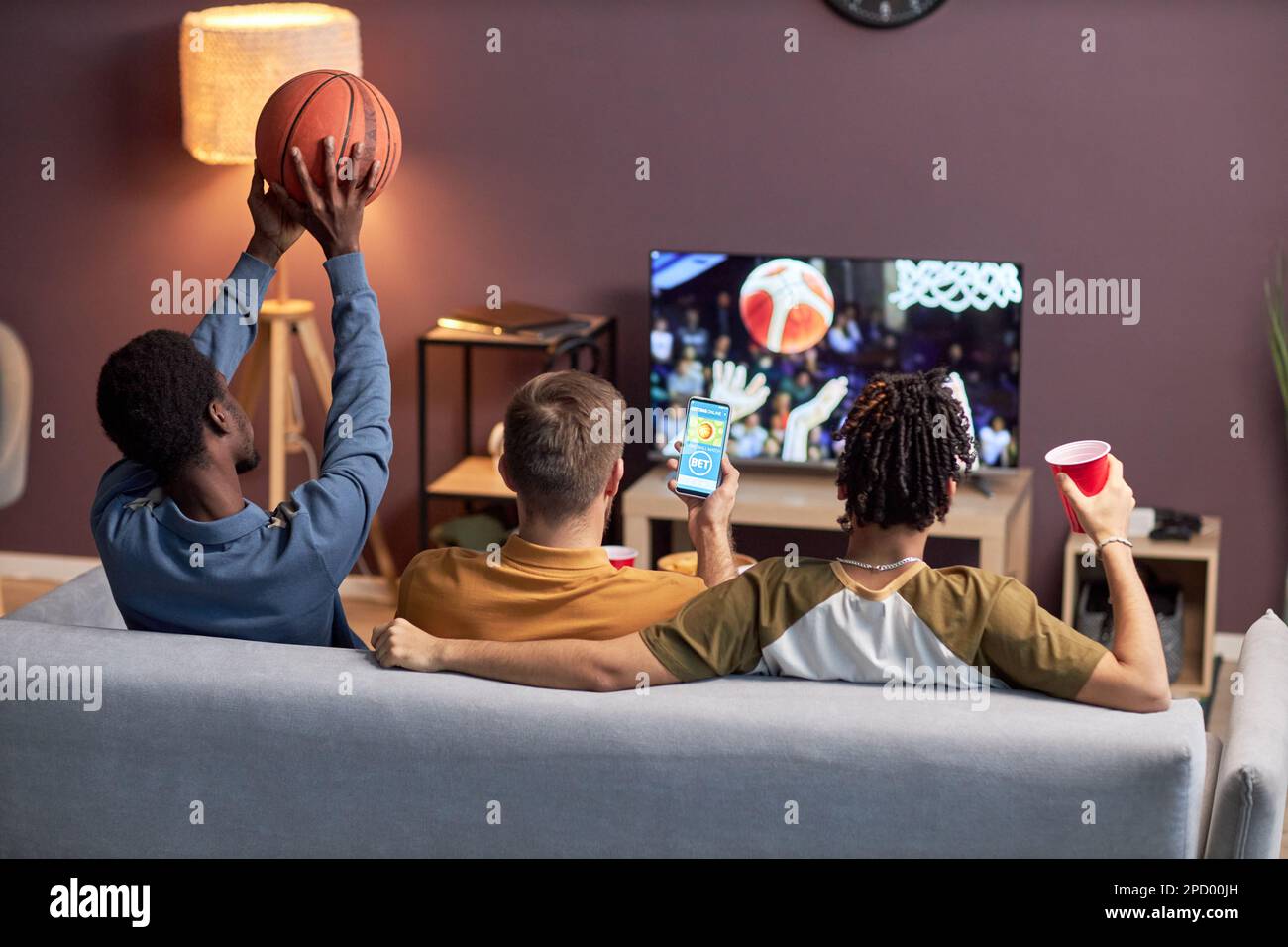 Back view at group of friends watching basketball match at home and ...