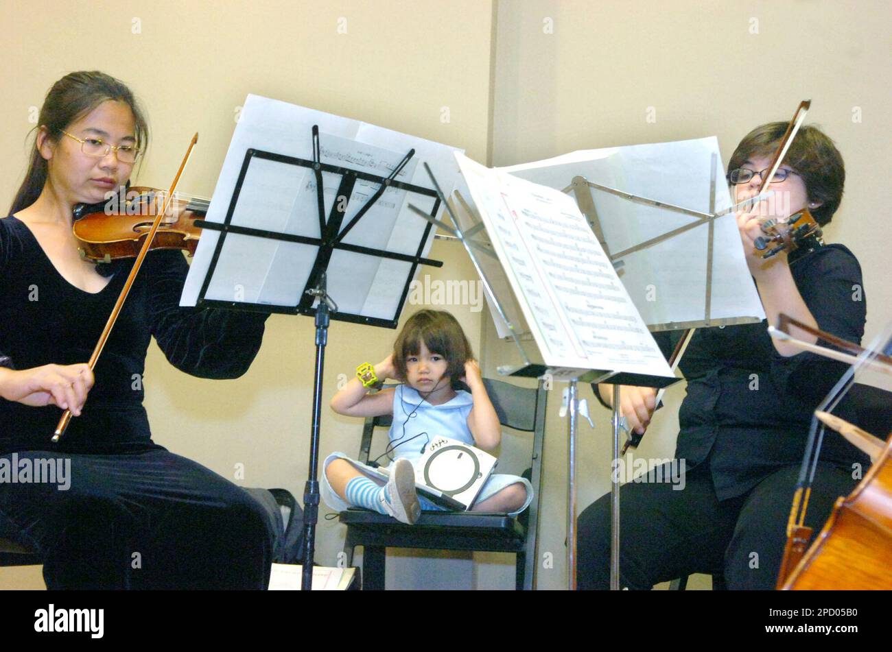 Three-year-old Jacqueline Tang, center, covers her ears during a ...