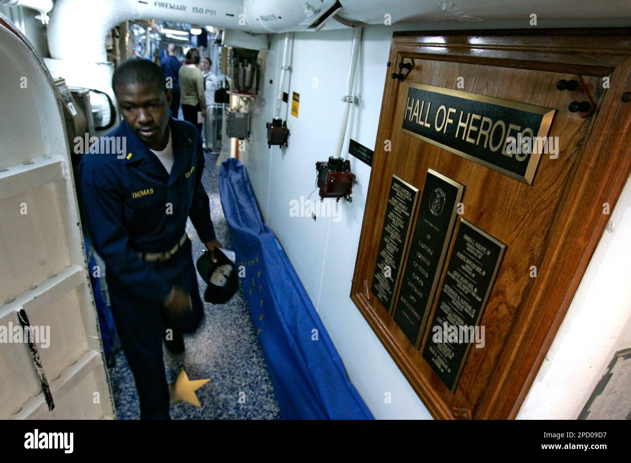A crew member aboard the USS Cole walks through the Hall of Heroes on ...