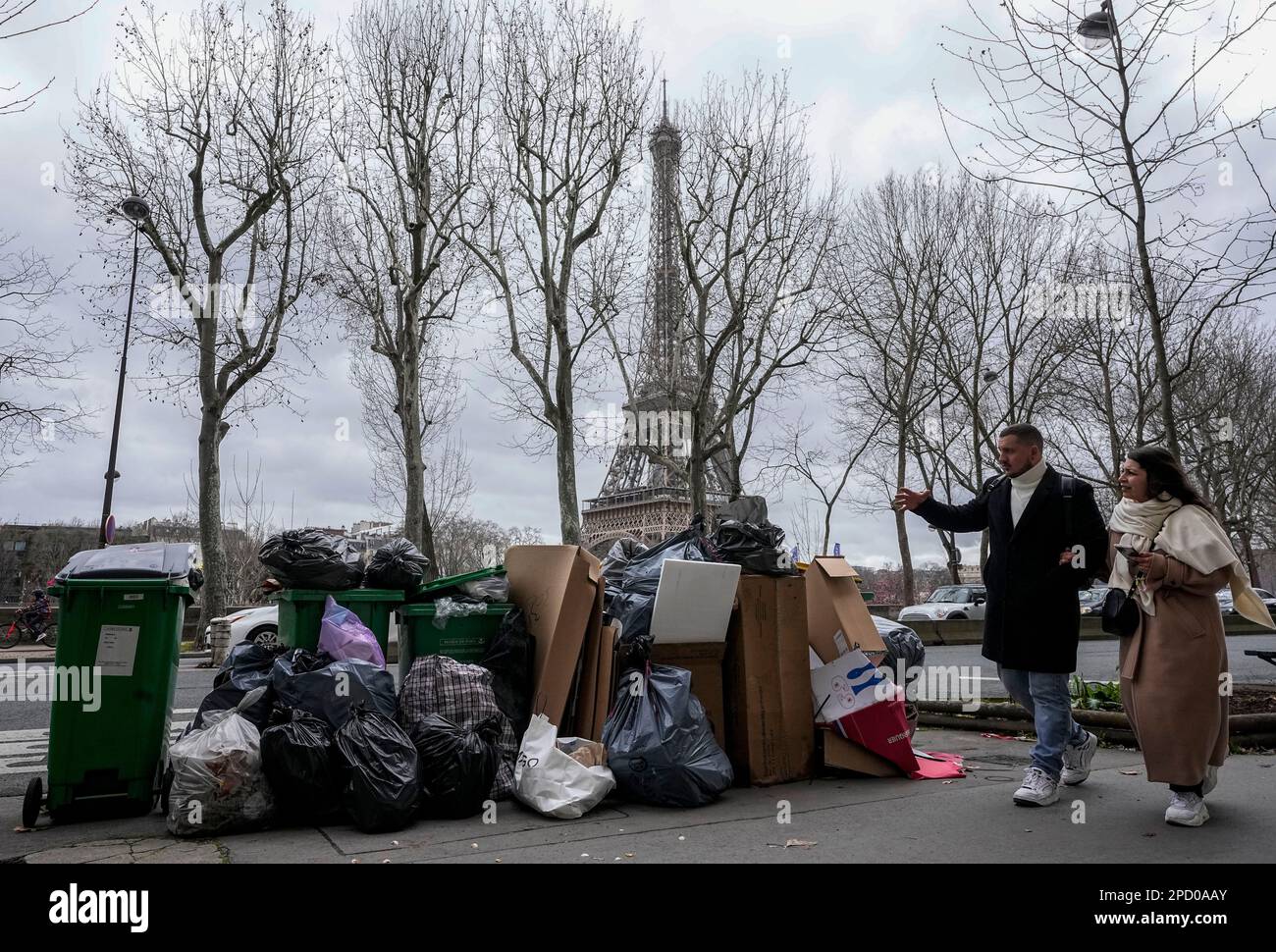 FILE- People walk past not collected garbage cans near the Eiffel Tower ...