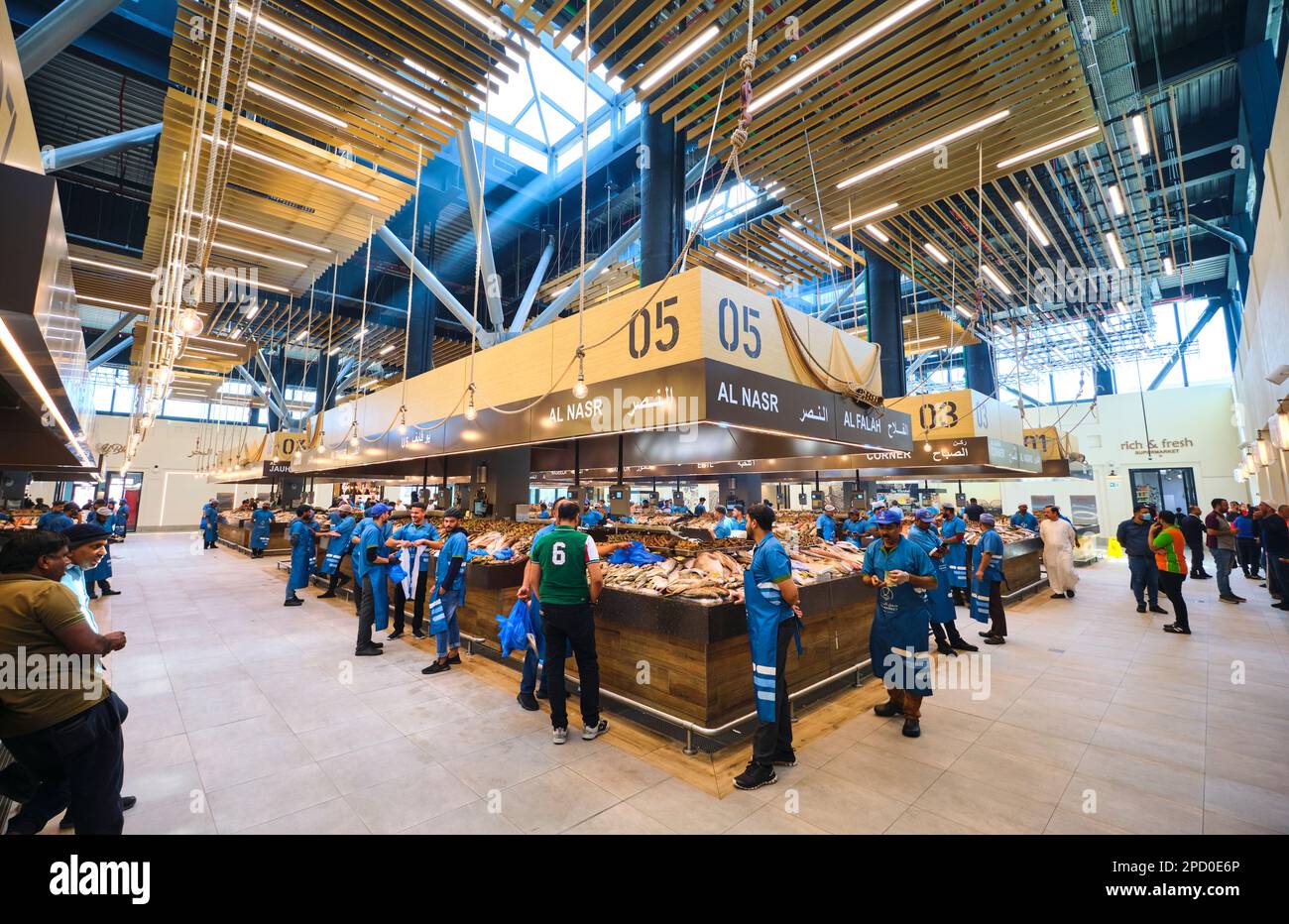 Various fish stalls, manned by vendors in blue uniforms. At the fish ...