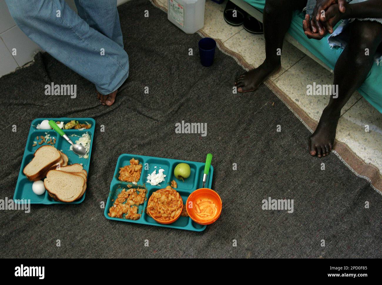 Food trays are seen on the floor as Refugees from the Sudan sit in a ...