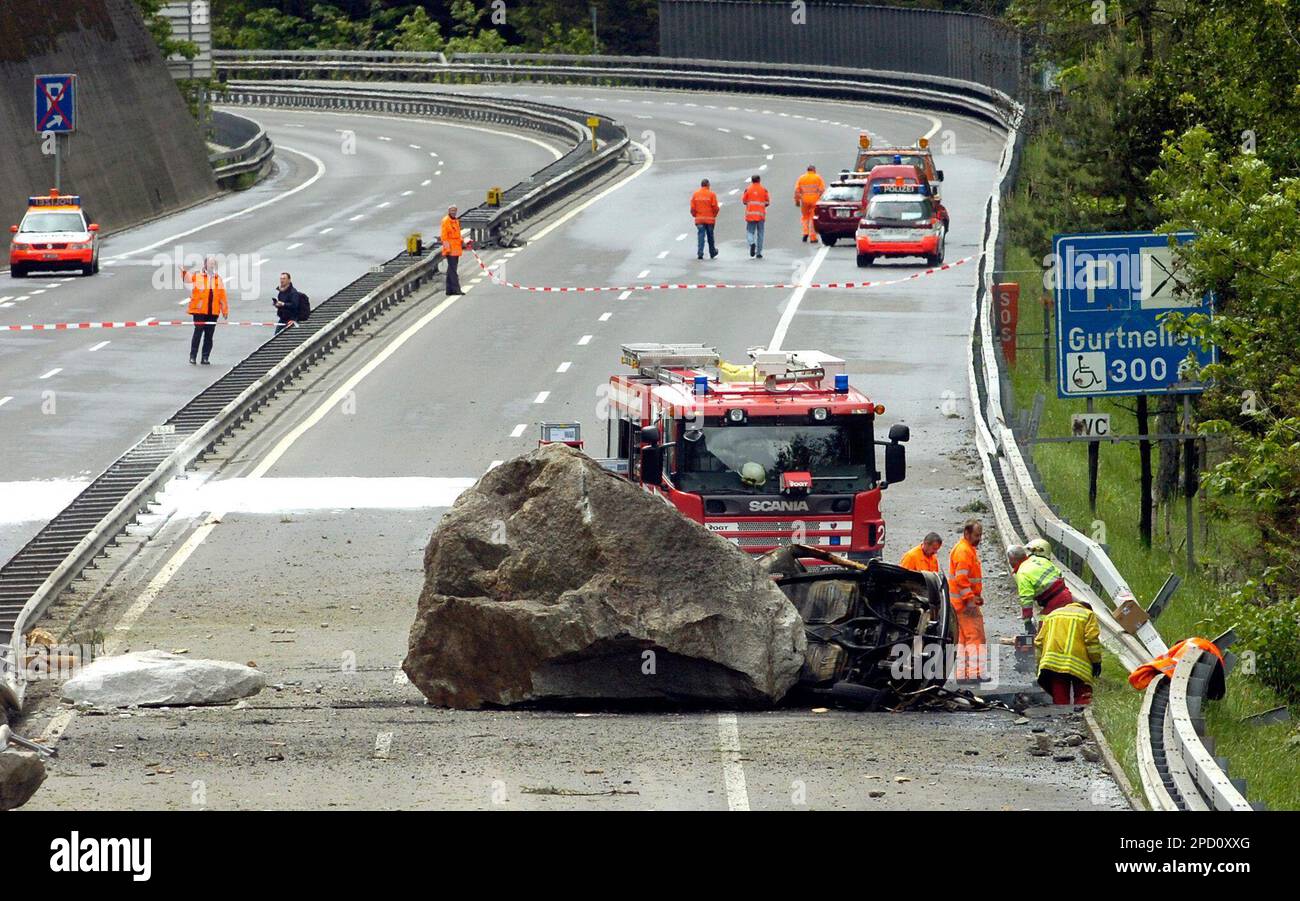Rescue workers recover a car lying behind a giant rock on the A2 ...