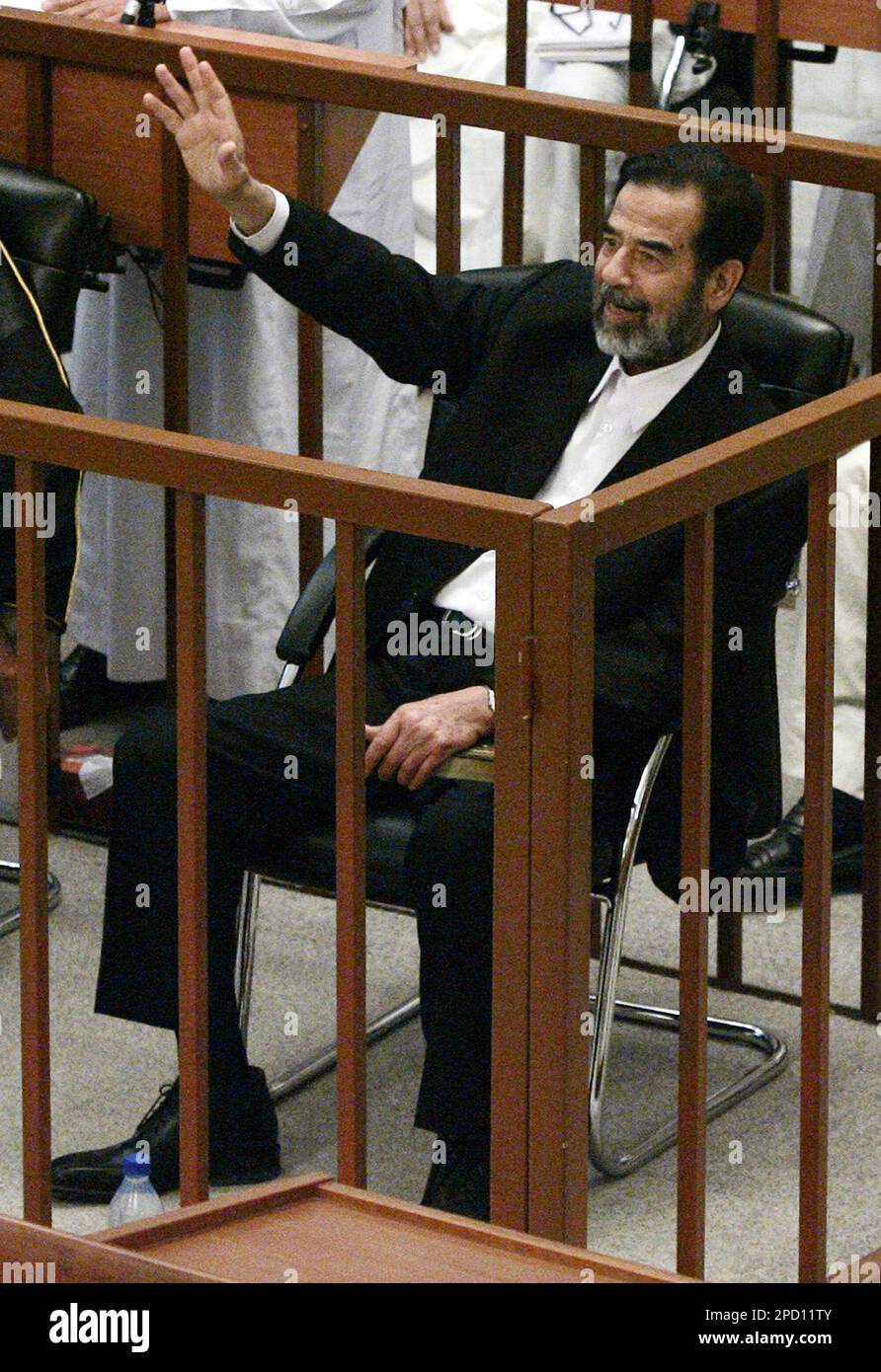 Former Iraqi President Saddam Hussein raises his right hand asking ...