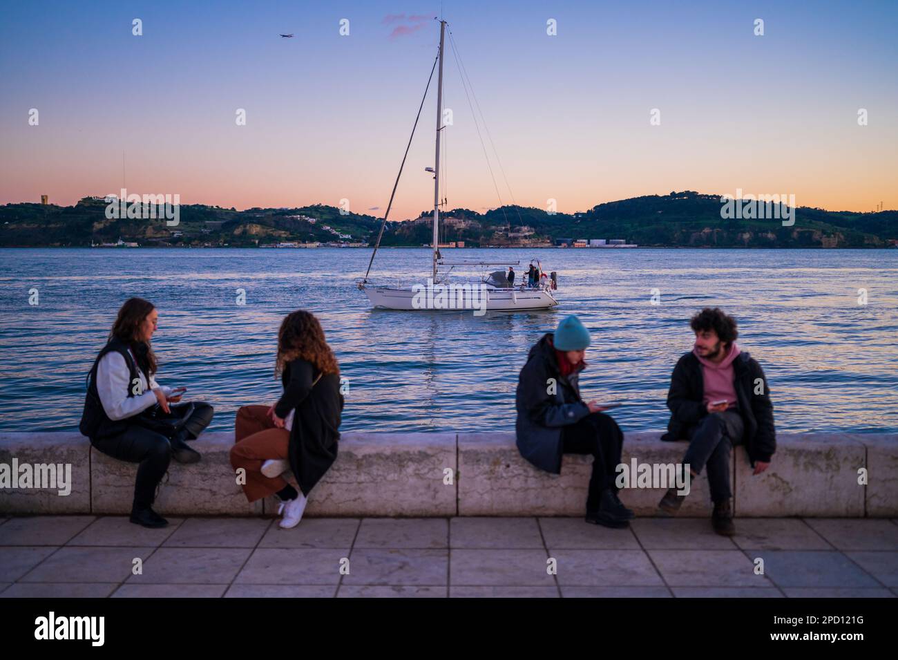 People enjoying the sunset in Belem promenade by Tagus River, Lisbon ...