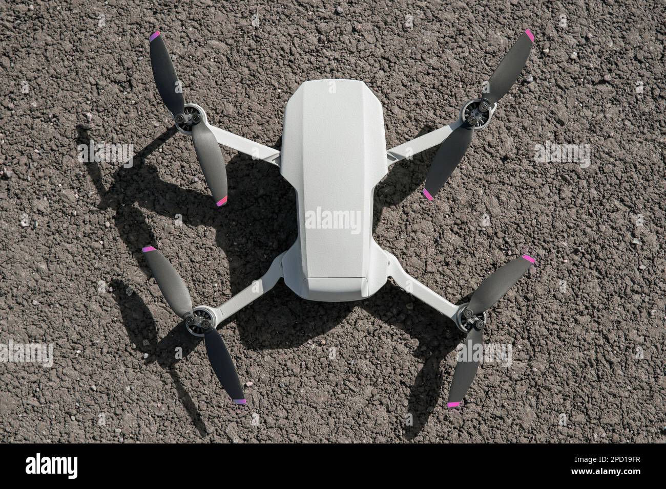 A modern drone, also known as a quadrocopter, stands on the pavement ...