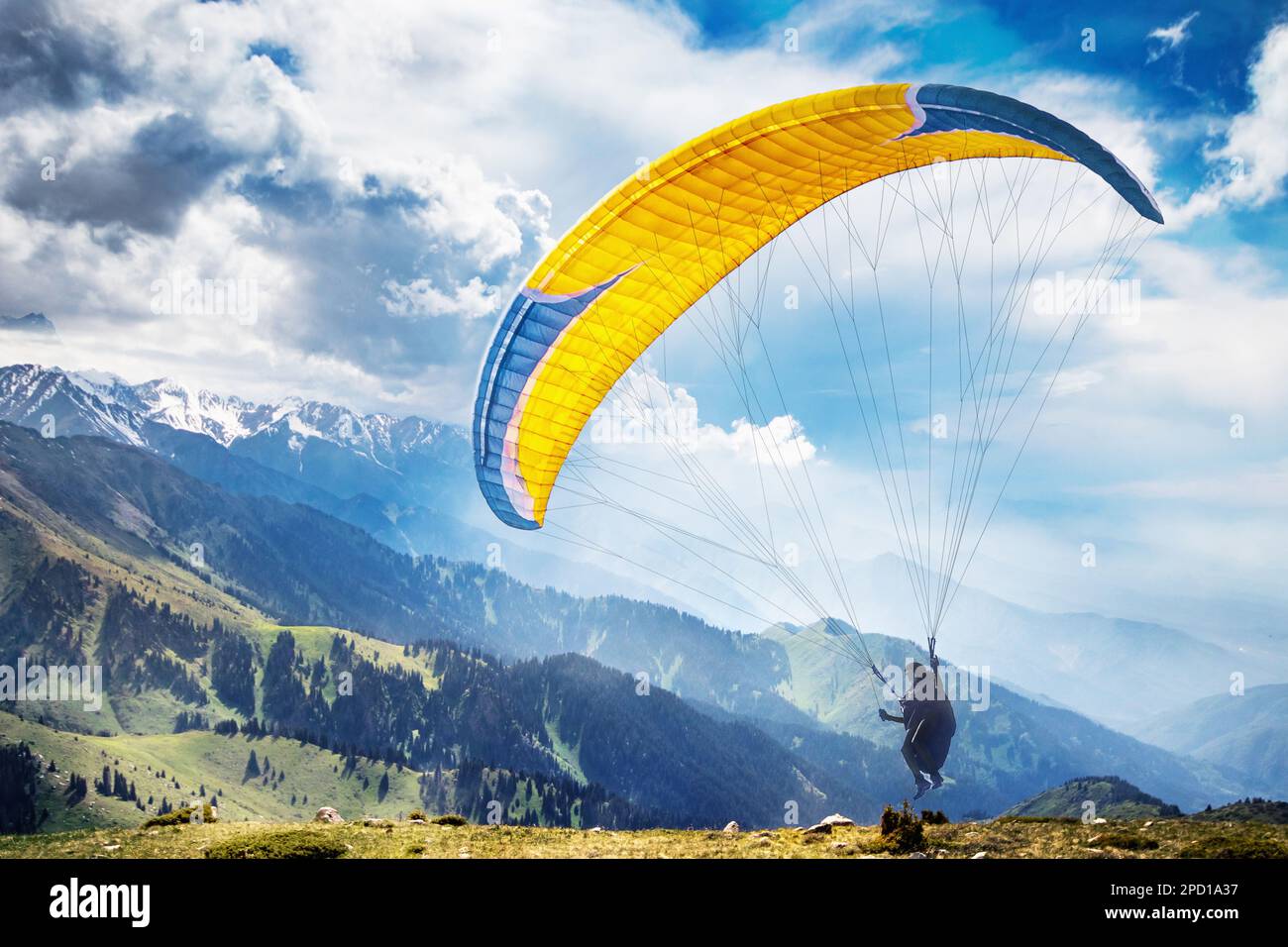 Amazing mountains landscape with a flying paraglider Stock Photo - Alamy