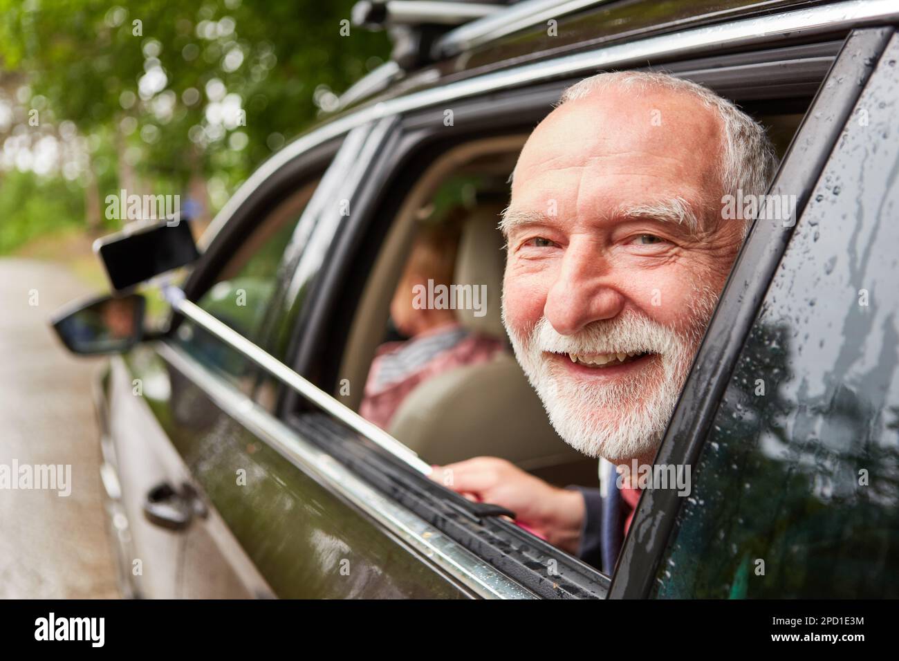 Portrait of happy senior man seen through window while traveling in car ...