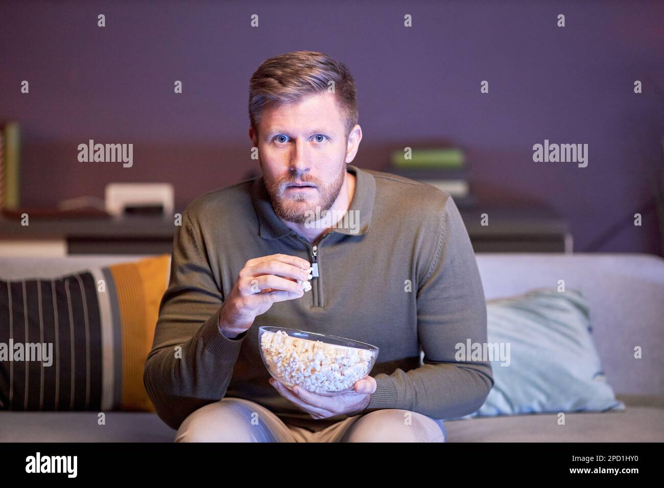 Portrait of one man watching sports match on TV at home in blue light ...