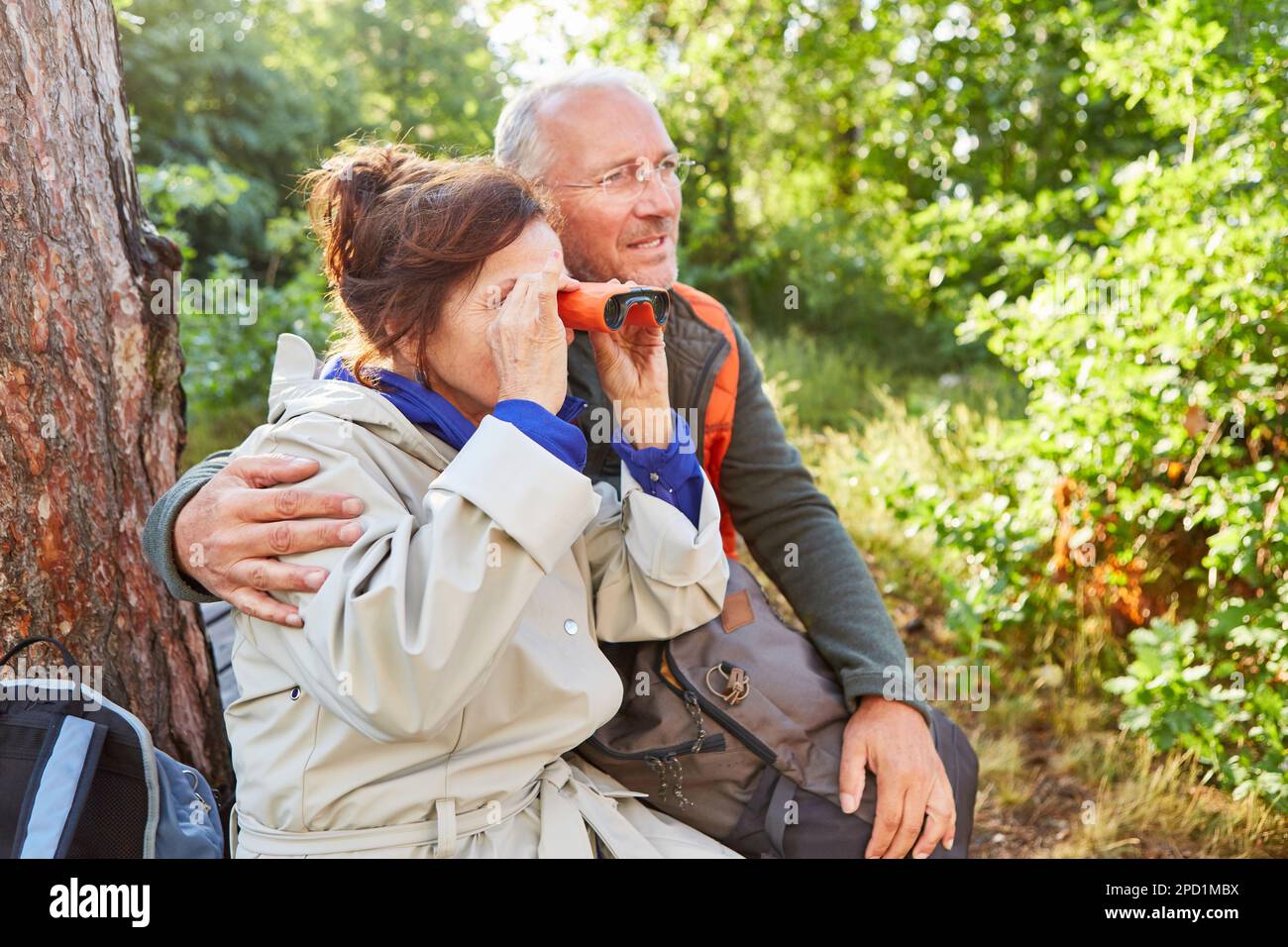 Elderly man and woman bird watching through binoculars while exploring ... Elderly man and woman bird watching through binoculars while exploring ...