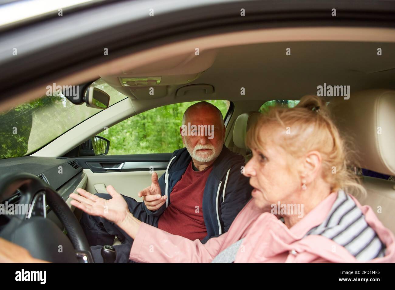 Angry elderly man gesturing while talking with woman driving car during ...