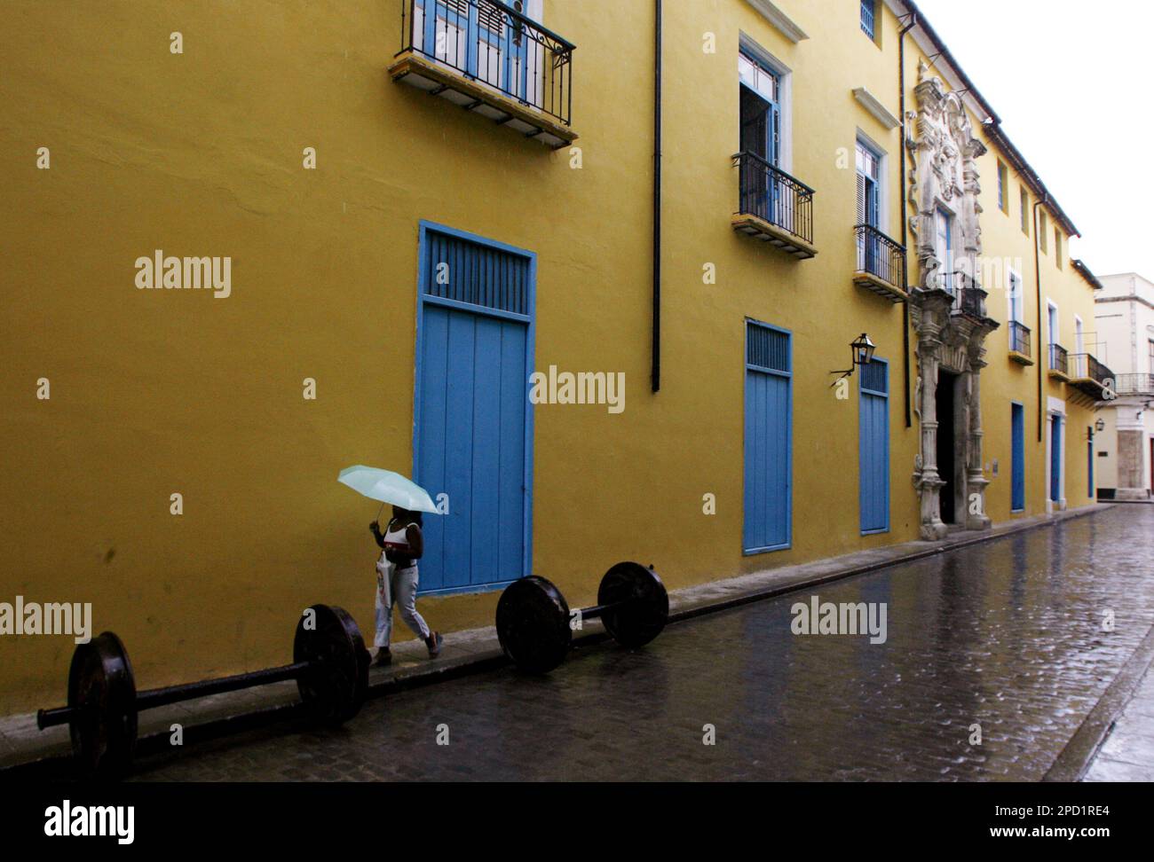 A Cuban woman uses an umbrella to shield herself from the rain as she ...