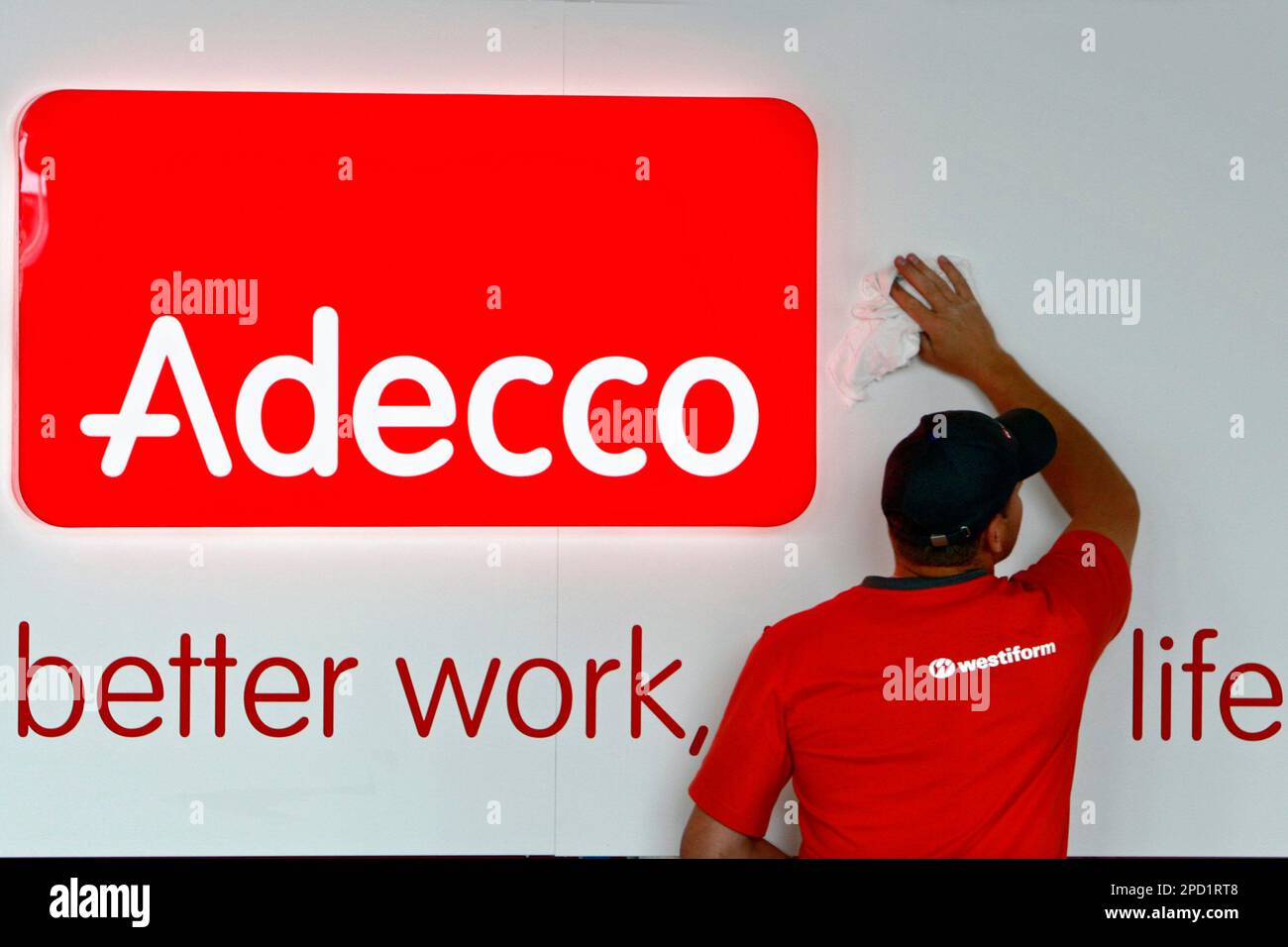A worker cleans a sign with the logo of the Swiss temporary work ...