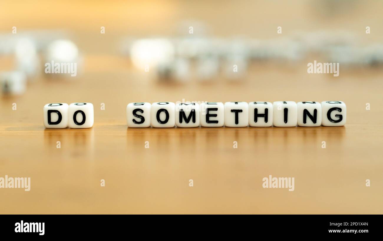Do something slogan in white block letter beads Stock Photo - Alamy