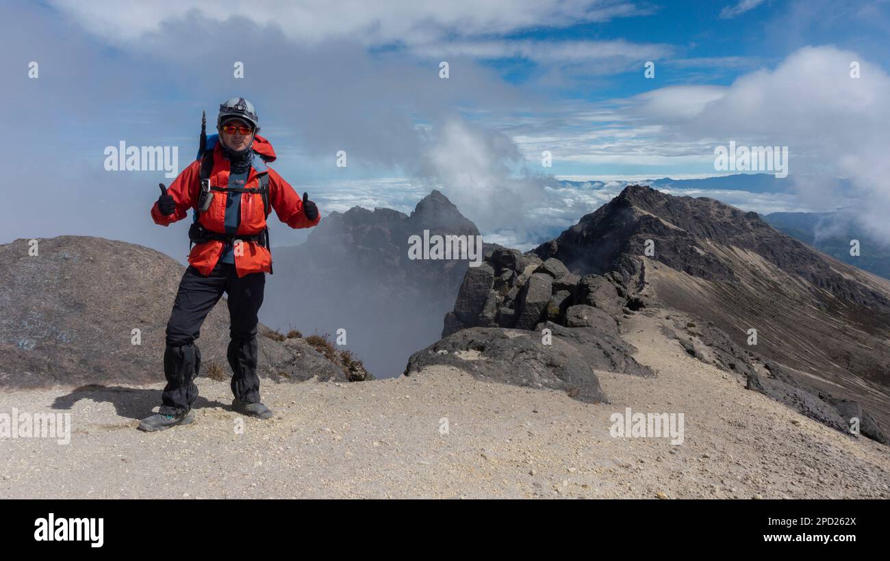 Young man climber standing on the summit of Guagua Pichincha volcano ...