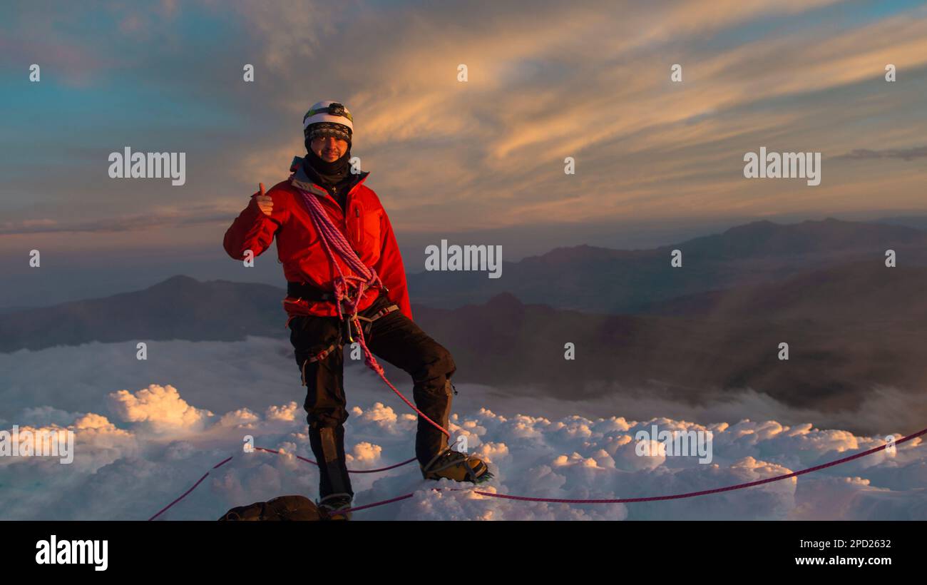 Young male climber standing on the summit of Cotopaxi volcano wearing ...