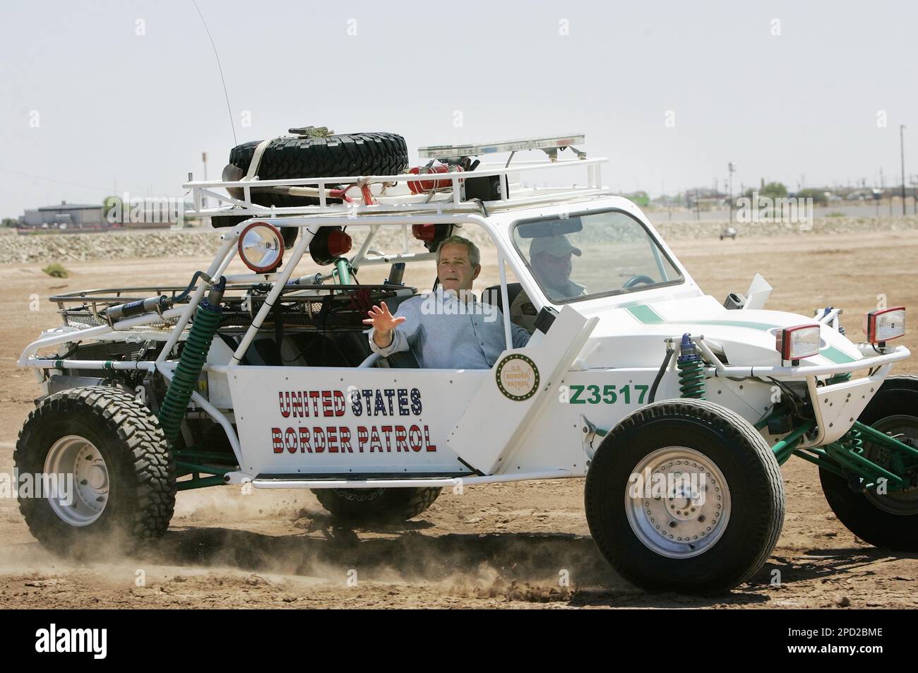 President Bush, left, waves as he rides a dune buggy driven by Rocky ...