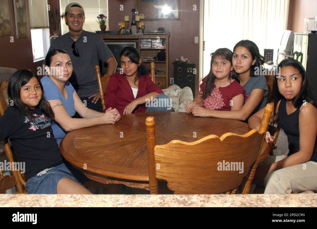 Mike Leija stands near members of his family gathered at a table ...