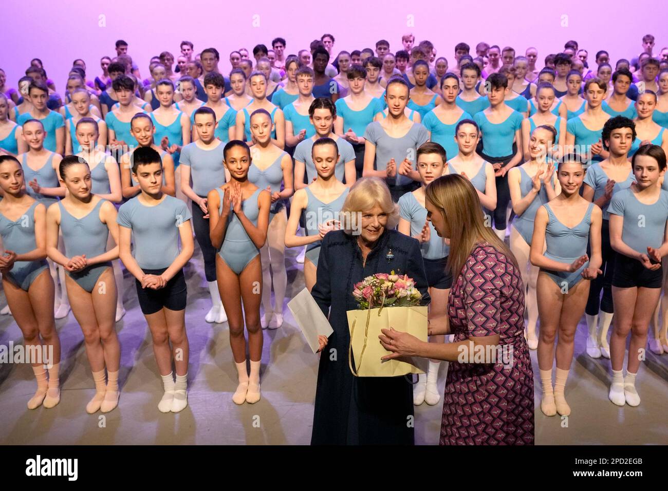 The Queen Consort receives flowers as she stands on stage with students ...