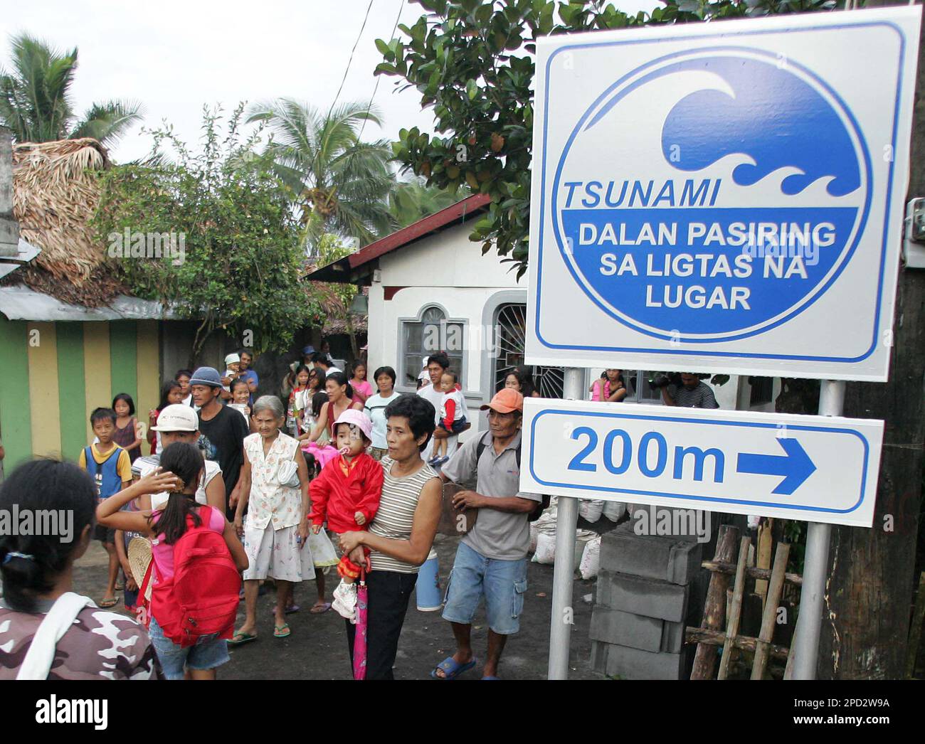 Filipino villagers evacuate their homes beside a sign that reads ...
