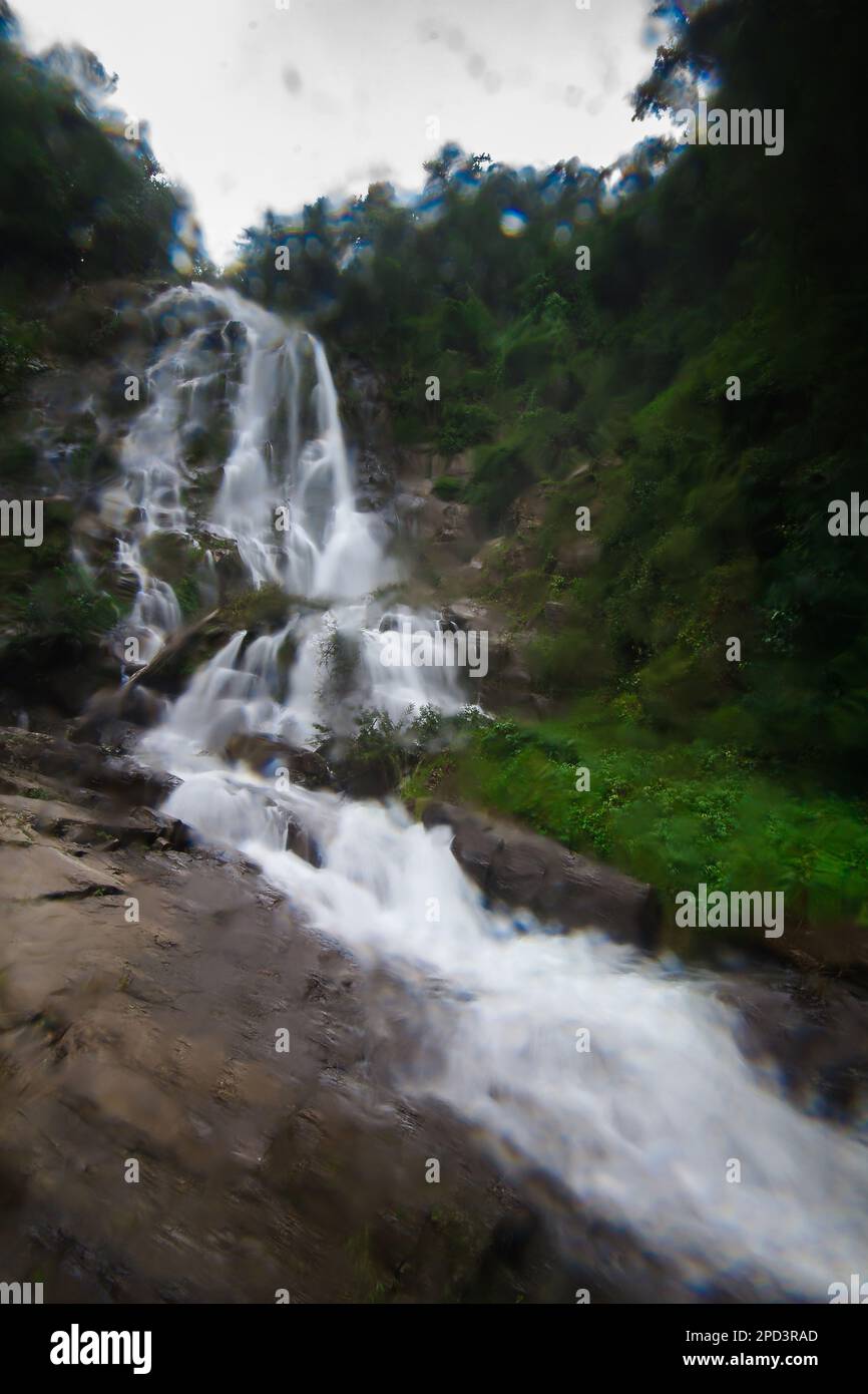 A natural waterfall flows down a long line from a cliff into a ...