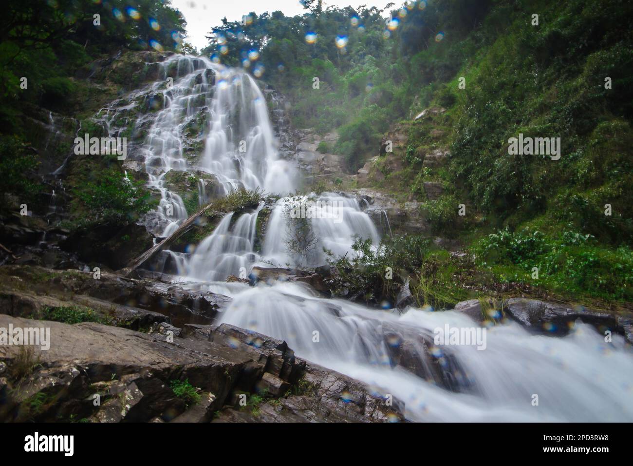 A natural waterfall flows down a long line from a cliff into a ...