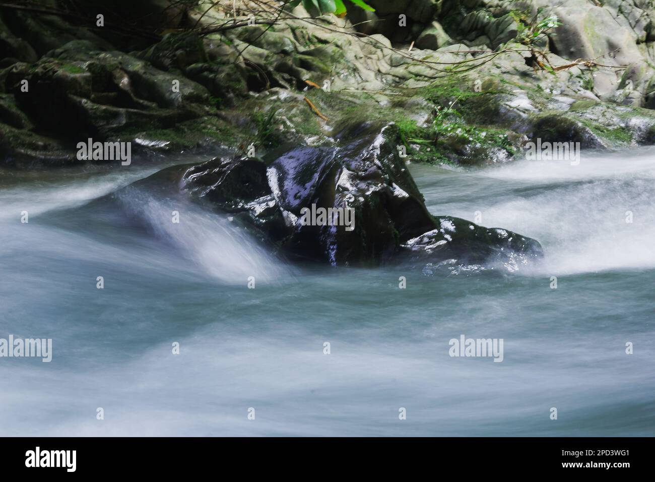 A natural waterfall flows down a long line from a cliff into a ...