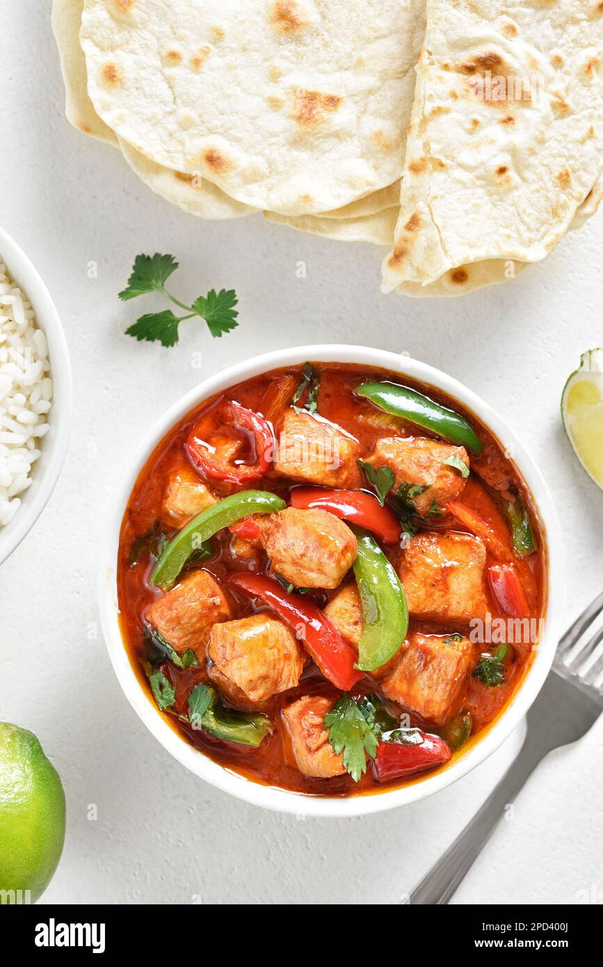 Thai style red chicken curry with vegetables in bowl over white ...