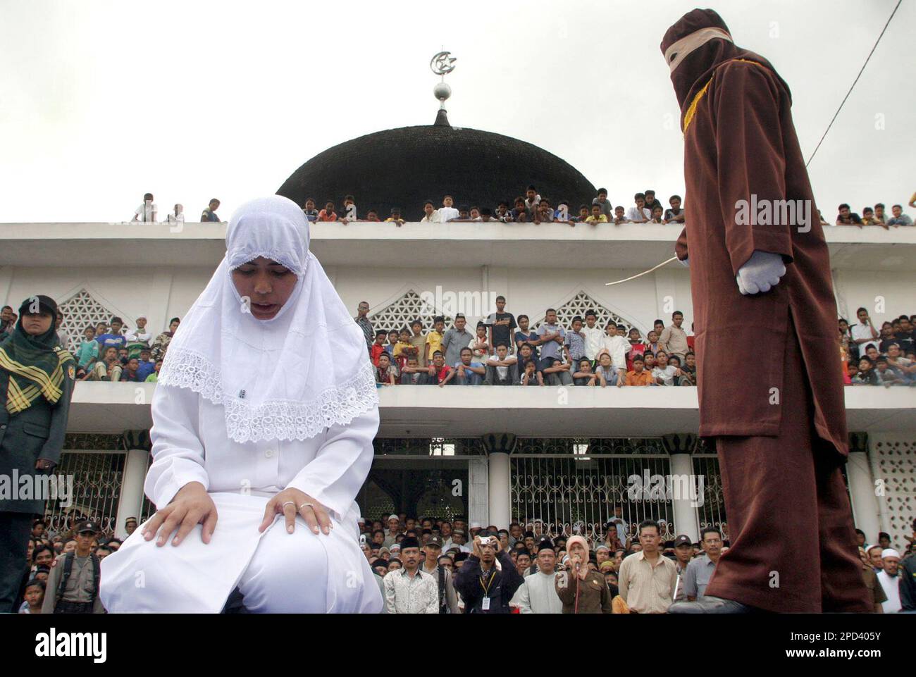 A Shariah official canes an Acehnese woman after she was convicted of ...