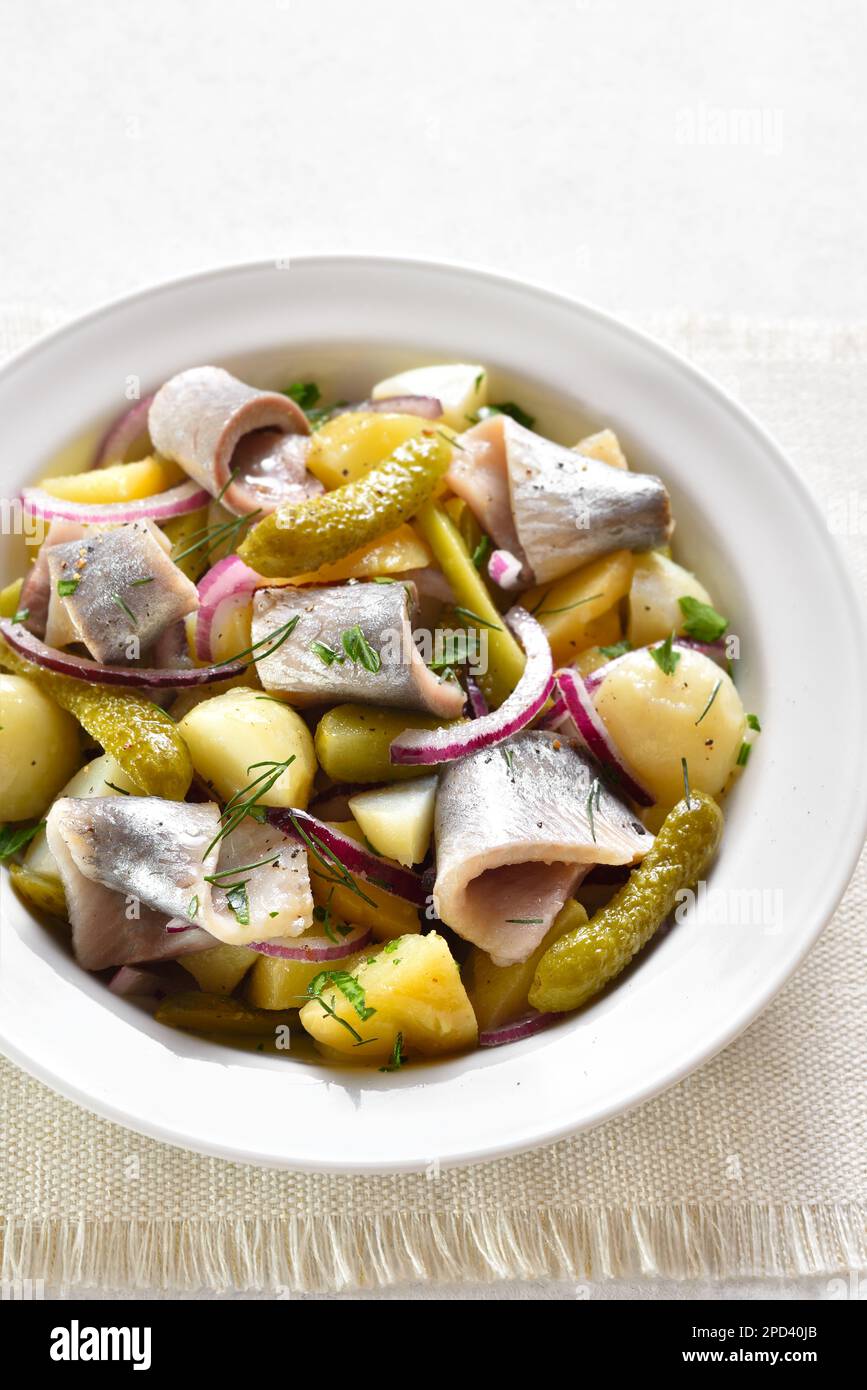 Herring salad with boiled potatoes, pickled cucumbers and red onion in ...