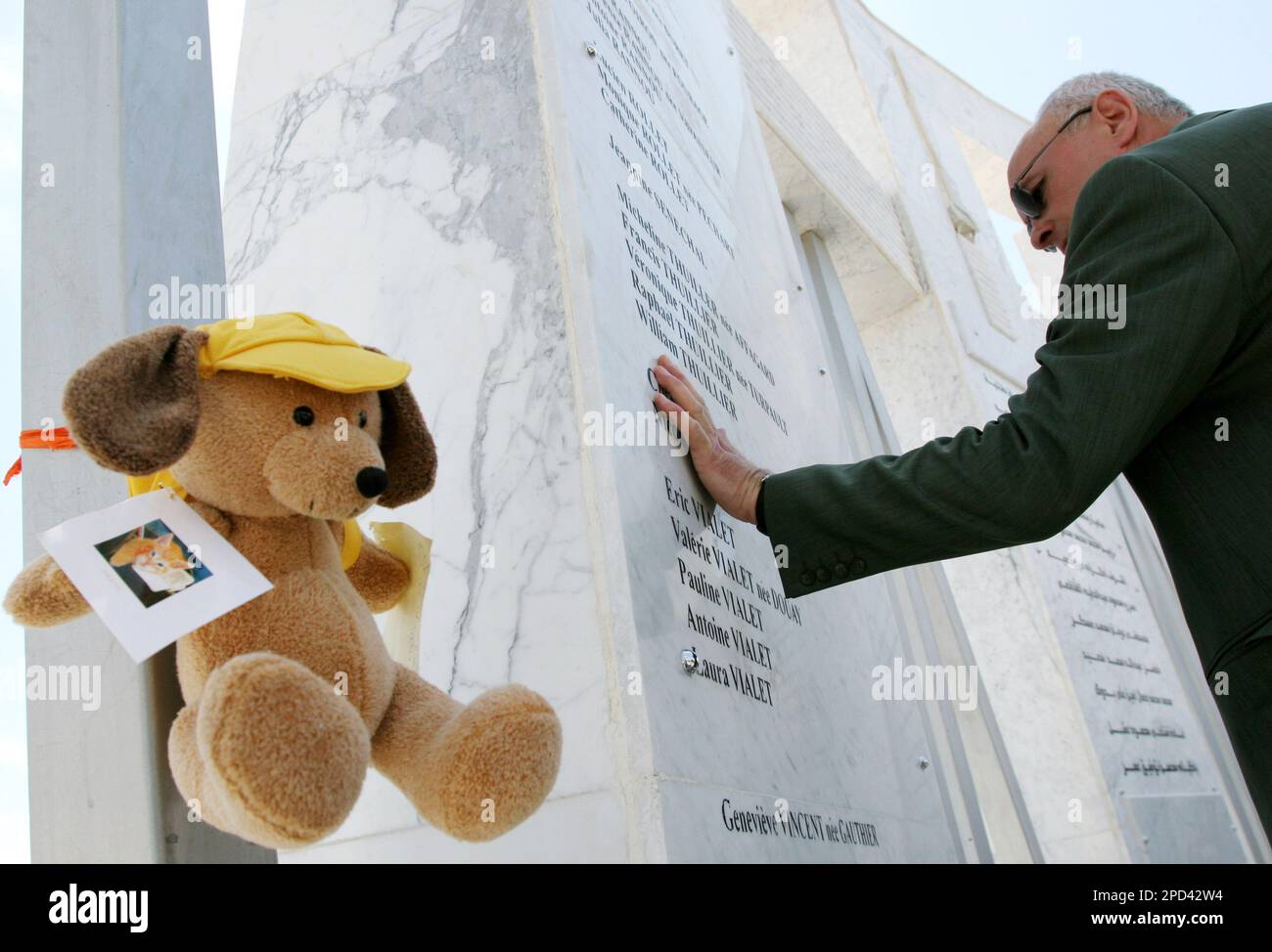 A mourner touches part of a large sculpture made of eight columns that ...