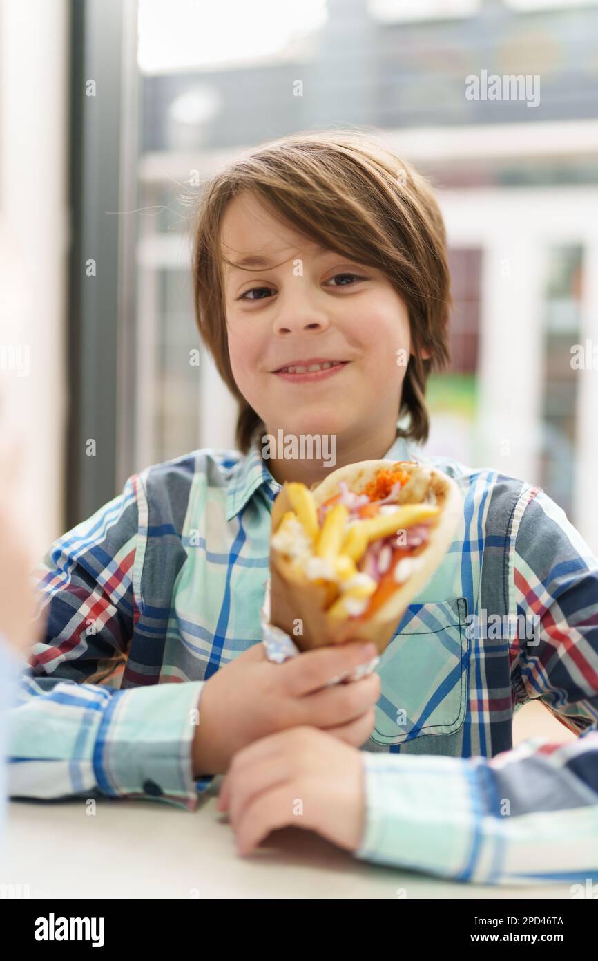 Happy little boy holding gyros wrap in hands. Portrait of cheerful ...