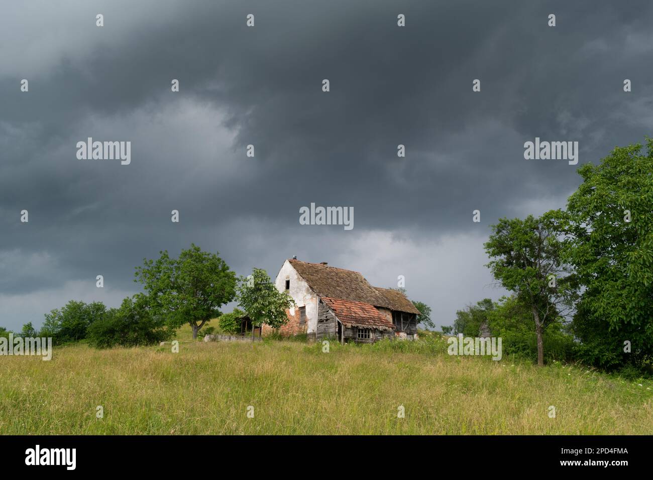 Storm clouds above abandoned countryside house, dark dramatic clouds above empty deserted ...